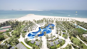 Resort com piscina central, praia e palmeiras.