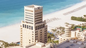Um hotel grande com vários andares, uma torre central e localização à beira-mar.