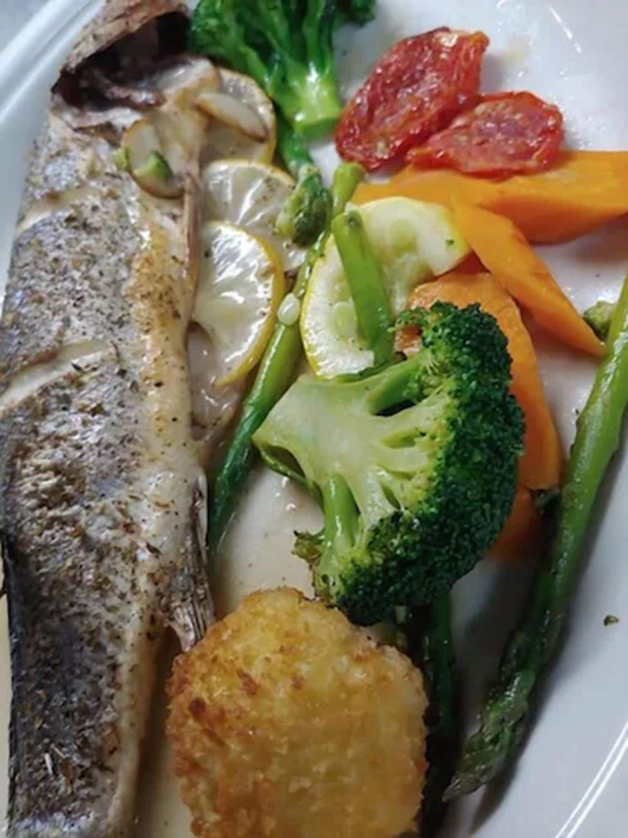 Um prato com filé de peixe, brócolis, cenouras e cogumelos.