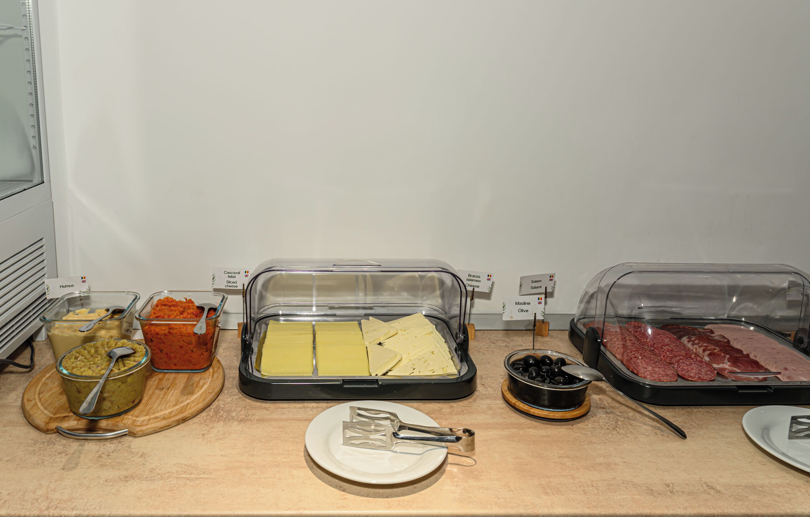 Buffet com diversos alimentos, incluindo queijo, carnes e azeitonas.