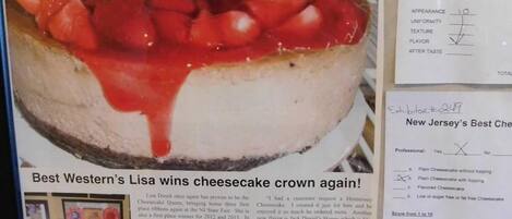 Um painel emoldurado exibindo um cheesecake com morangos por cima, com o título 'Rivertown'.