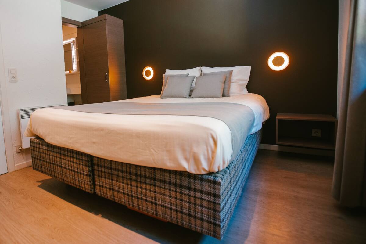 Quarto com cama, guarda-roupa e mesa de cabeceira.