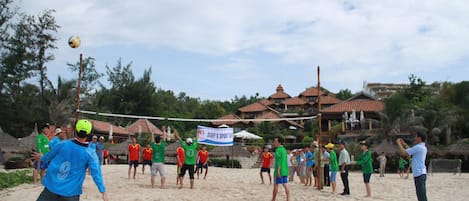Jogo de voleibol de praia com jogadores vestindo camisas de cores diversas.