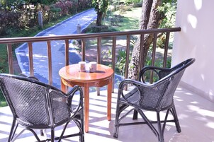 Varanda com cadeiras de vime e uma pequena mesa redonda, com vista para um caminho no jardim.