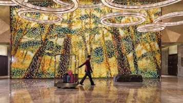 Um saguão com uma parede em mosaico e um carrinho de bagagem.