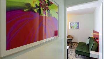 Uma sala de estar moderna com um grande quadro abstrato, um sofá verde, uma mesinha e uma cadeira.