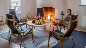 Um quarto aconchegante com lareira, cadeiras de madeira, uma mesa redonda e luminárias pendentes.