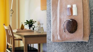 Quarto com mesa de jantar, cadeira, luminária, planta em vaso e toalha com artigos de higiene pessoal na parede.