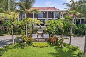 Um resort com uma escadaria central, vegetação exuberante e um edifício com telhado de telhas vermelhas.