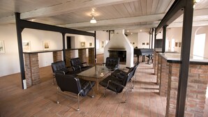 Um quarto espaçoso com uma mesa de vidro cercada por poltronas de couro, uma lareira de tijolos e obras de arte nas paredes.