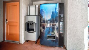 Um corredor com uma porta, uma máquina de vendas e uma geladeira com exibição panorâmica.