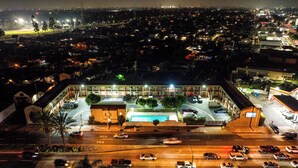 Vista aérea de um hotel com estacionamento, vários andares e uma piscina.