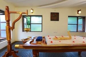 Um quarto com uma mesa de massagem de madeira, um candeeiro a óleo de latão e uma toalha azul.