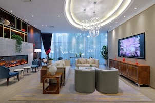 Uma sala de estar moderna com lareira, assentos confortáveis, uma televisão grande e um lustre decorativo.