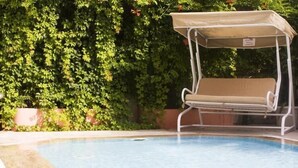 Uma piscina com cadeira de balanço e toldo.