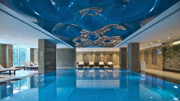 Piscina interior moderna com teto refletor e espreguiçadeiras ao longo das laterais.