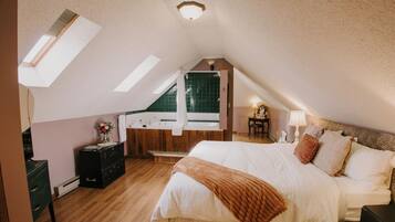 Quarto com uma cama grande, cômoda de madeira, penteadeira e banheiro com banheira.