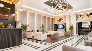 Um lobby moderno com balcão de recepção, área de estar e um grande lustre.