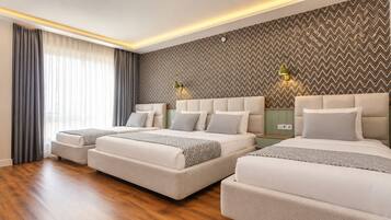 Quarto de hotel com três camas, parede estampada e piso de madeira.
