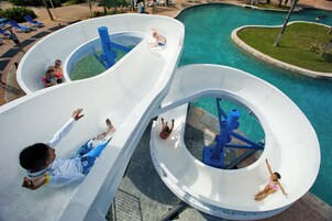 Um toboágua com várias pistas e área de piscina com espreguiçadeiras.