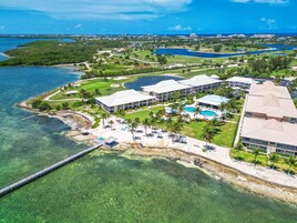 Vista aérea de um resort com vários edifícios, um campo de golfe e uma área de praia com águas cristalinas.