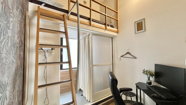 Quarto estilo dormitório com beliche, escrivaninha com computador e cadeira.