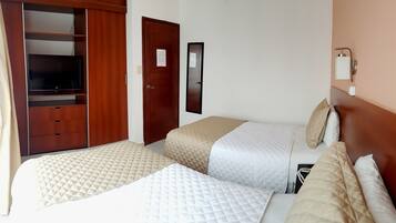 Quarto de hotel com duas camas, um guarda-roupa, uma televisão e um espelho.