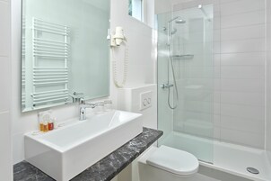 Casa de banho moderna com lavatório branco, cabine de duche em vidro e sanita.