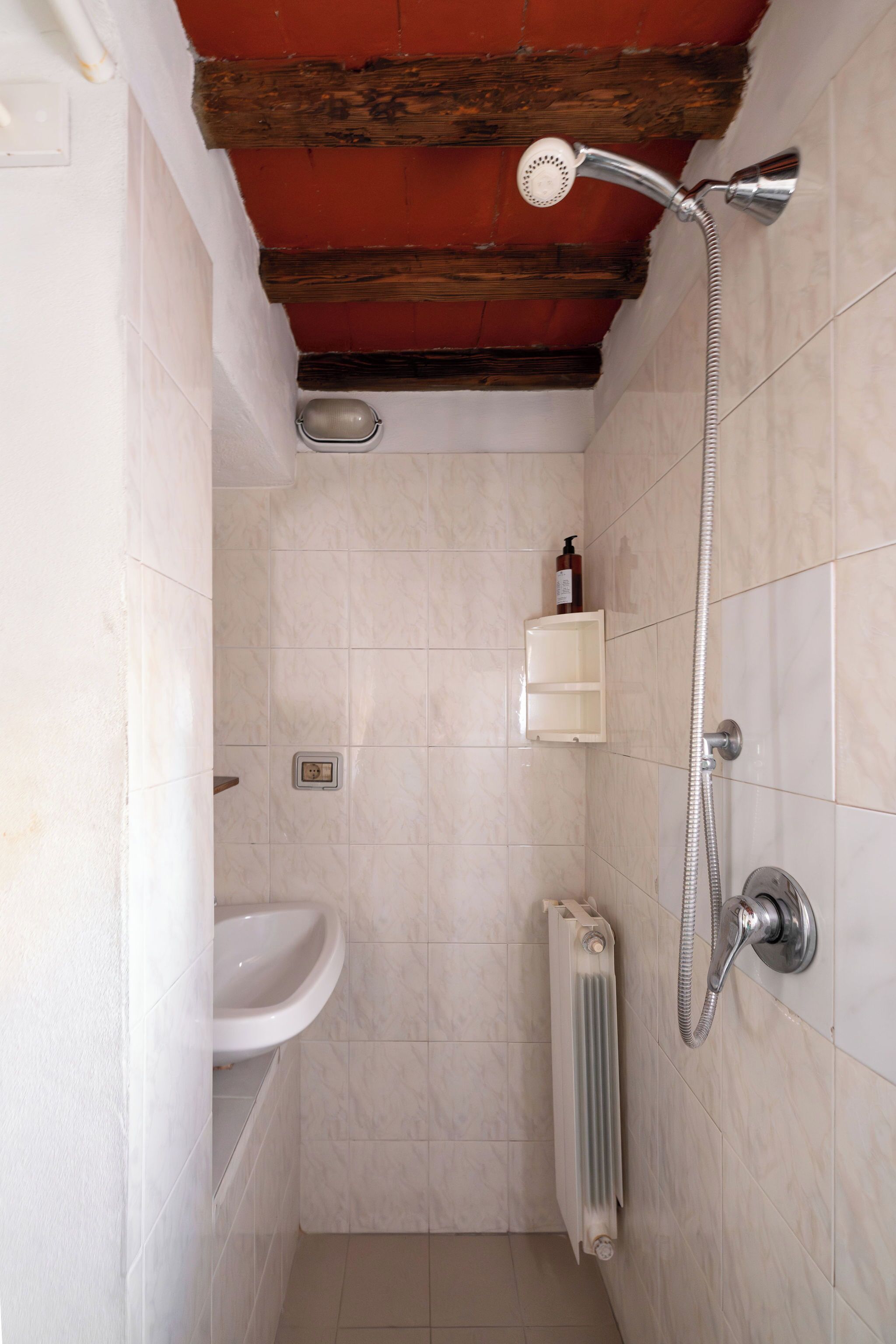 Uma casa de banho pequena com chuveiro, lavatório e radiador.