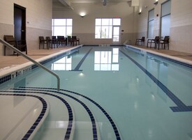 Piscina interna com marcações claras, cadeiras ao redor e uma porta com a inscrição '3º Andar Proibido Mergulho'.