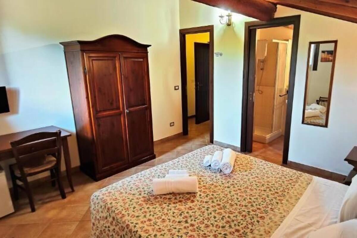 Quarto com cama, escrivaninha, guarda-roupa e espelho.