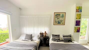 Quarto com duas camas, mesa de cabeceira, abajur e janela com cortinas.