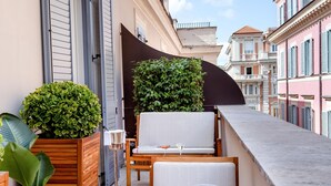 Uma área de refeições ao ar livre com uma mesa posta para dois, um vaso de planta e vista para o horizonte da cidade.