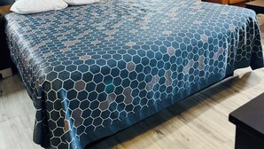 Quarto de hotel com uma cama, uma mesinha de cabeceira, um abajur e uma cadeira laranja.