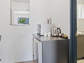 Uma cozinha compacta com micro-ondas, chaleira e cafeteira, além de um pequeno espaço para café.