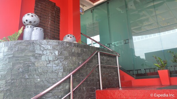 Um edifício moderno com fachada vermelha, parede de pedra e entrada de vidro.