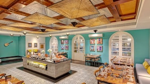 Restaurante com serviço de buffet, vigas de madeira no teto e paredes verde-água.