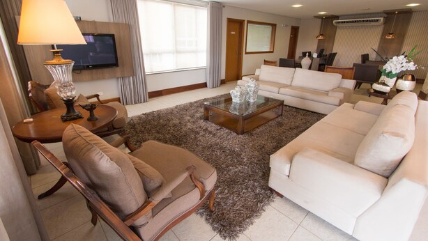 Uma sala de estar moderna com sofá, poltrona, mesa de centro e TV fixada na parede.