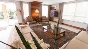 Uma sala de estar moderna com um sofá, poltronas, uma mesa de centro e uma televisão.