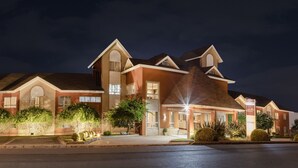Um hotel grande, de vários andares, com entrada imponente, várias janelas e arredores bem iluminados.