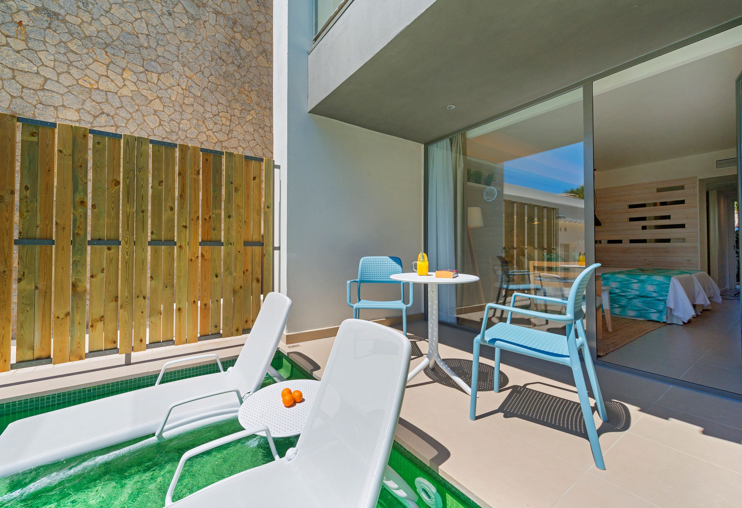 Uma área de piscina com espreguiçadeiras, uma mesa e um cercado de madeira.