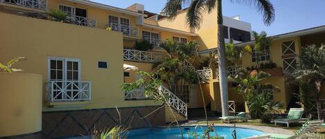 Um hotel com piscina, área de estar externa e palmeiras.