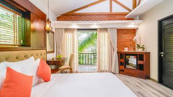 Quarto de hotel com uma cama grande, uma escrivaninha, uma cadeira, uma mesa pequena, um armário e uma varanda com vista para o verde.