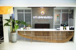 Um balcão de recepção com uma placa indicando 'Holiday Suites Business District' e um logotipo acima.