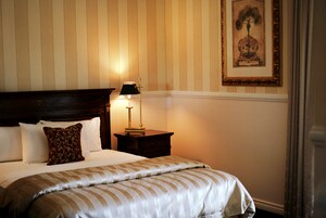 Uma cama bem arrumada com roupa de cama listrada, um abajur e um quadro na parede.