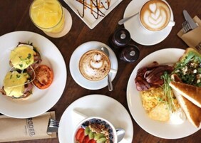 Uma mesa de café da manhã com diversos pratos, incluindo ovos, torradas e uma bebida de café.