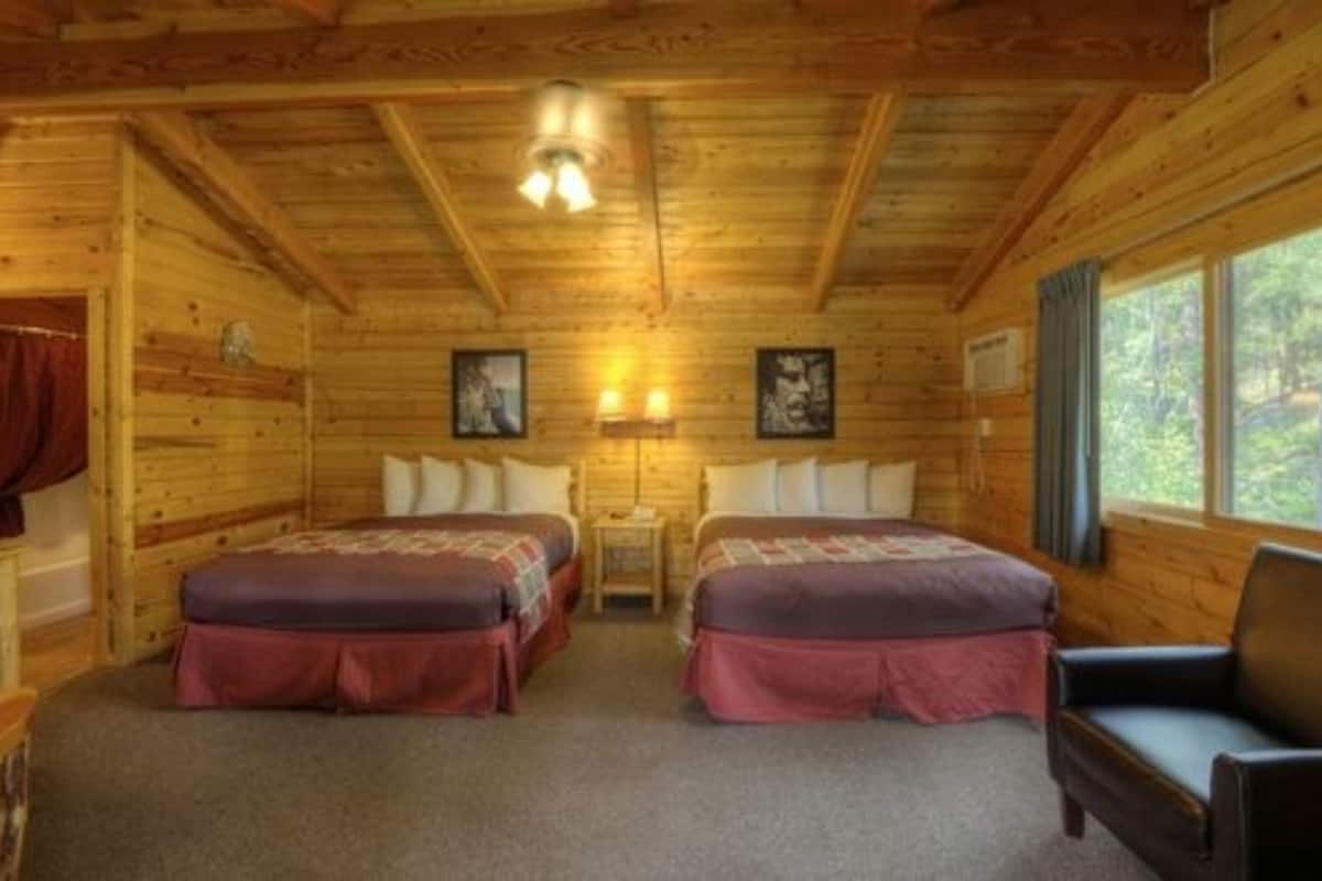 Uma cabana com duas camas, uma mesa pequena e uma cadeira.
