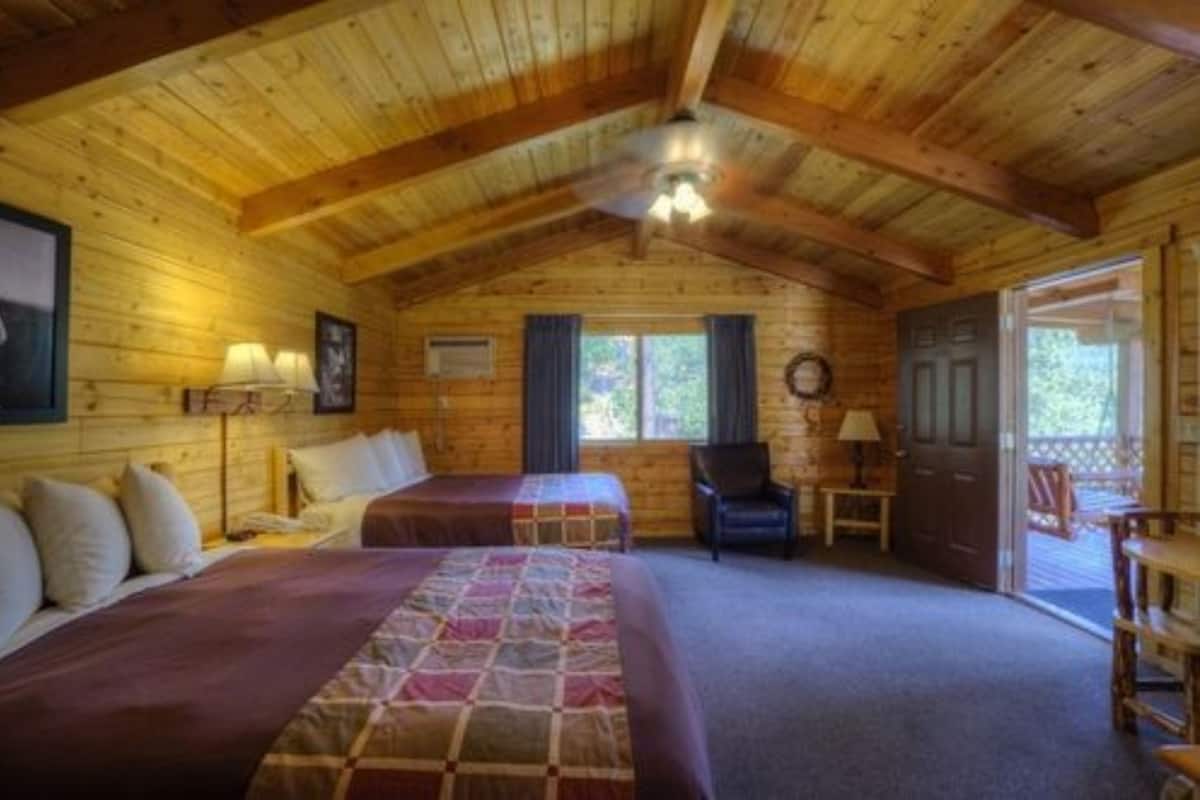 Quarto de cabana de tronco com uma cama grande, uma cadeira e uma escrivaninha.