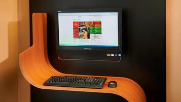 Monitor Lenovo fixado numa secretária de madeira curva, com um teclado e rato.