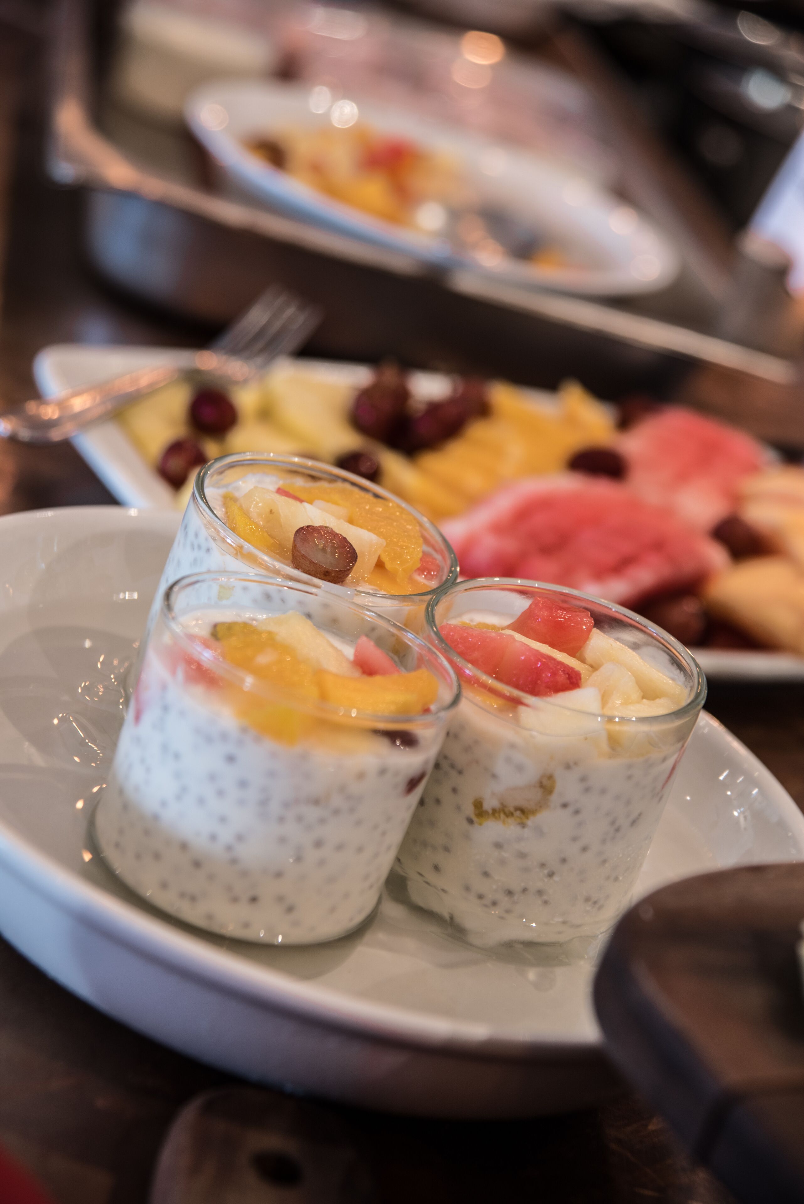 Três taças de sobremesa com fruta sobre um prato.